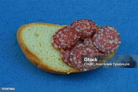 빨간 살라미 소시지 조각과 긴 덩어리가 파란색 테이블에 놓여 있습니다 0명에 대한 스톡 사진 및 기타 이미지 0명 갈색