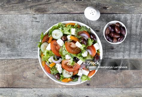 흰 접시에 페타와 야채가있는 전통적인 그리스 샐러드 페타 치즈 토마토 오이 올리브 나무 배경에 양파가있는 신선한 야채 샐러드 상단 전망 건강한 식생활에 대한 스톡 사진 및