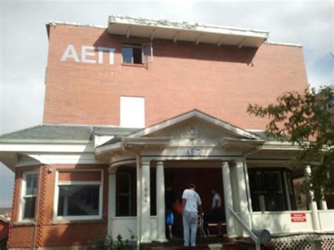 Two People Are Entering The Front Door Of A Red Brick Building That Says Aeti
