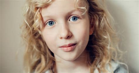 밝은 중성 베이지색 배경에 긴 머리를 가진 아름다운 웃는 백인 금발 소녀의 근접 촬영 초상화 자연스러운 감정을 가진 예쁜 진짜 여자 아이 행복한 정통 어린 시절 라이프