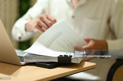 노트북 앞에 앉아서 나무 사무실 책상 위에서 서류를 작업하고 있는 정체불명의 사업가 30 34세에 대한 스톡 사진 및 기타 이미지 30 34세 검색 기업 문화