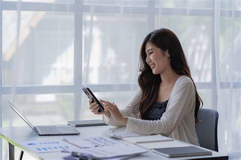 스마트 폰을 사용하여 노트북으로 회계 업무를 수행하고 사무실에서 재무 보고서 그래프를 작성하는 아시아 사업가 금융에 대한 스톡