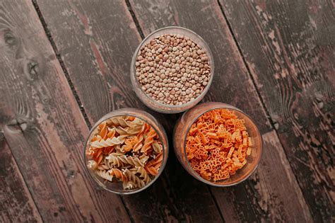 부엌에서 스마트 식품 저장옵션 원시 파스타와 가트 등을 어두운 나무 테이블에 보관하기 위한 3개의 유리 항아리 곡초류에 대한 스톡 사진 및 기타 이미지 Istock