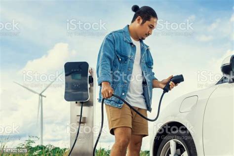 Ev 자동차와 풍력 터빈을 재생 에너지의 개념으로 사용하는 진보적인 남자 교통수단에 대한 스톡 사진 및 기타 이미지 교통수단
