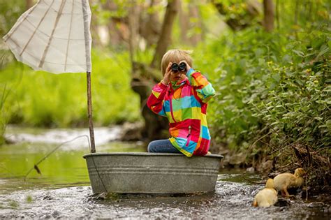 귀여운 아이 화려한 재킷을 입은 소년 작은 강에서 보트와 오리와 놀고 항해와 보트를 타고 재미있고 어린 시절의 개념 아이에 대한 스톡 사진 및 기타 이미지 Istock