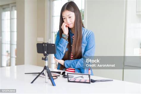 아름 다운 아시아 영향력 여자 기록 스마트폰 카메라를 사용 하 여 자습서를 구성 스트레스와 긴장 입 물고 손톱에 손으로 불안