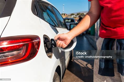 흰색 자동차에서 휘발유나 디젤 연료에 연료를 보급하기 위해 자동차 노즐을 여는 남자 교통 에너지 위기 석유 위기의 개념 가스 펌프의 가격 위기 속에서 가득 찬 탱크 가격에