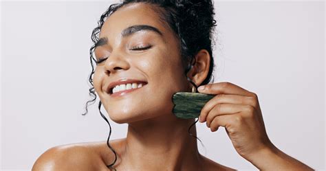 스킨케어 미소 그리고 웰빙 피부과 및 고급 스파를 위한 괄사 스톤을 사용한 여성 몸 화장품 및 숙녀는 옥 결정 노화 방지 또는 흰색 스튜디오 배경에 자연 치료로 빛납니다