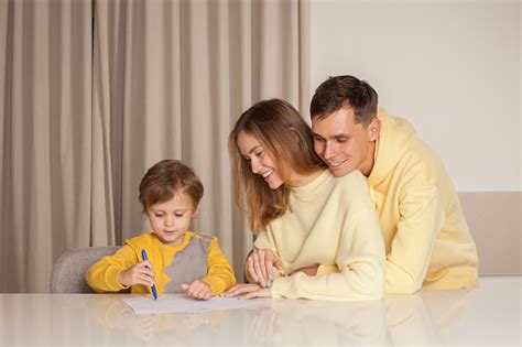 사랑스러운 가족 노란 옷을 입은 귀여운 부모와 아이 아들이 테이블 옆에 앉아 그림을 그린다 2 3 살에 대한 스톡 사진 및 기타 이미지 Istock