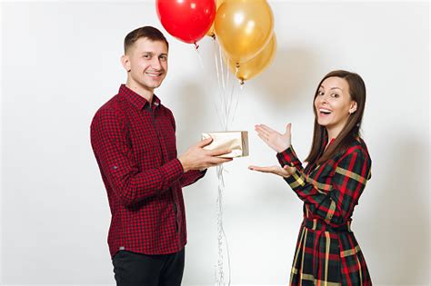 아름 다운 젊은 행복 미소 커플 사랑에 여자와 남자와 황금 선물 상자를 들고 제시 하 고 빨강 노랑 흰색 바탕에 생일 축 하 풍선 격리 휴일 파티 개념입니다 2명에 대한