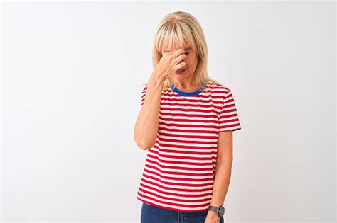 캐주얼 스트라이프 티셔츠를 입고 있는 중년 여성은 고립된 흰색 배경 위에 서서 피로와 두통을 느끼는 코와 눈을 문지르며 피곤합니다 스트레스와 좌절 개념 T 셔츠에 대한 스톡