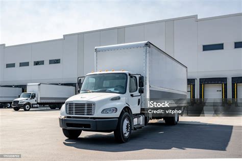 일정에 따라 적절한 적재 시간을 기다리는 다른 세미 트럭과 함께 창고 주차장에 서 있는 현지 배송을 위한 긴 상자 트레일러가 있는 인기 있는 소형 장비 세미 트럭 세미