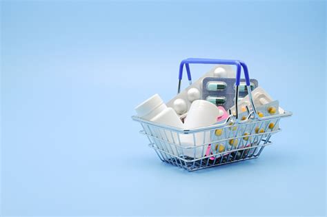구매 및 쇼핑 의학 개념 파란색 배경에 상점 바구니에 다양한 캡슐 정제 및 의약품이 있습니다 건강 관리 건강 보험 및 제약 회사를위한 창의적인 아이디어 복사 공간 개념에