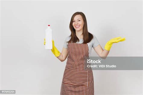 젊은 주부 노란색 장갑에 웃 고 줄무늬 앞치마 흰색 배경에 고립 매력적인 여자는 세척 및 청소 스폰지 대 한 청소기 액체 병을 들고 광고에 대 한 공간을 복사 가사 집안일에