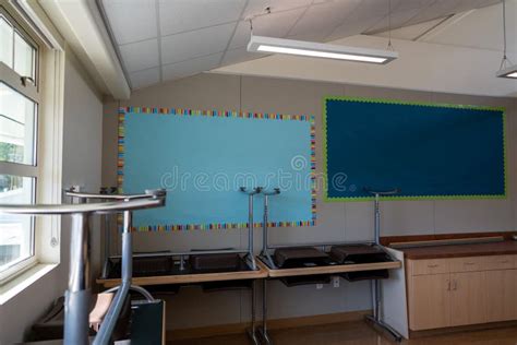 Corner Of Empty Classroom With Tables And Blank Posters Before School