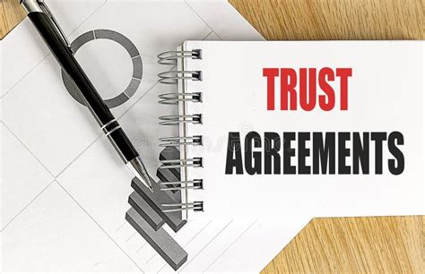 Notepad With Trust Agreements Text Black Pen And Financial Charts On A Wooden Desk Stock Image