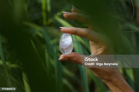 프랑스 매니큐어와 여성의 손은 Vumfit Imbuilding 또는 명상투명 보라색 자수정 요니 계란을 들고 크리스탈 석영 계란 손에 녹색 배경 야외 건강한 생활방식에 대한