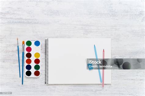 연필 페인트 와 브러시 흰색 나무 배경에 예술가의 빈 스케치북 예술 적인 모형 템플릿입니다 상단 보기 복사 공간 학교 개념으로