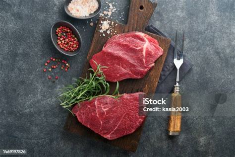 생 쇠고기 스테이크 어두운 콘크리트 배경의 도마에 로즈마리 소금 후추를 곁들인 차돌박이 생 신선한 립아이 스테이크 생 쇠고기 스테이크와 요리 용 향신료 0명에 대한 스톡