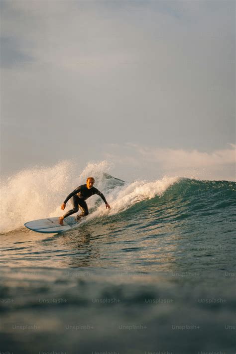 서핑 보드 위에서 파도를 타는 남자 사진 Unsplash의 대양 이미지