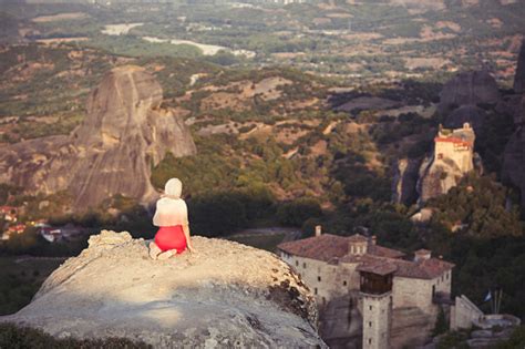 빨간 드레스 스카프에 외로운 소녀 바위의 가장자리에 앉아와 메 테오 라의 수도원 반대 기도 바위와 그리스 테 살 리에 유성의