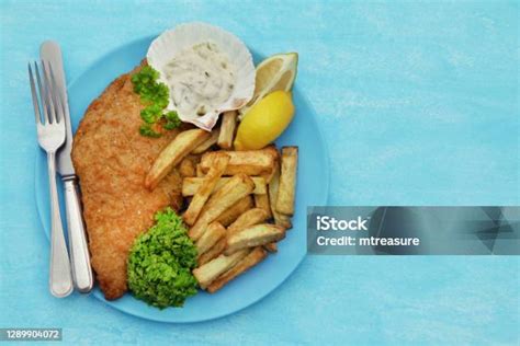 청록색 접시에 피시 앤 칩스 이미지 레몬 슬라이스 타르타르 소스를 포함하는 가리비 껍질과 파슬리 금속 나이프와 포크 청록색 배경 복사 공간 높은 전망으로 장식 피쉬 앤