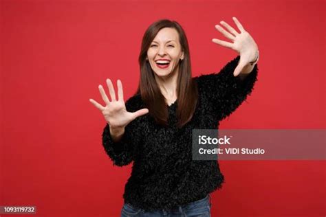 검은 모피 스웨터 서 카메라에 손바닥을 보여주는에 쾌활 한 젊은 여자의 초상화 스튜디오에서 밝은 빨간 벽 배경에 고립 사람들이 진심으 감정 라이프 스타일 개념 복사 공간을