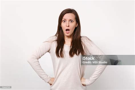 가벼운 옷을 입을 열어 입고 젊은 여자 충격의 초상화 무기와 함께 서 있는 Akimbo 스튜디오에서 흰색 배경에 고립 사람들은 진심으로 감정 라이프 스타일 개념입니다 복사