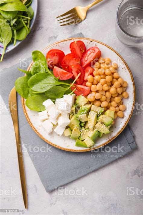 아보카도 병아리콩 페타 치즈 신선한 시금치 토마토와 물 한 잔을 곁들인 부처님 그릇 건강한 채식 해독 균형 잡힌 식사를 위한 컨셉 맨 위 보기 공간을 복사합니다 0명에 대한