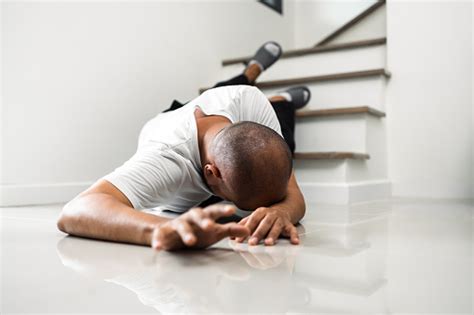 한 젊은이가 기절하여 집 계단에서 쓰러집니다 그는 사고로 부상을 입었고 계단에서 쓰러졌습니다 그는 아무도 도움을받지 못하는 집에서 혼자였습니다 부러진 뼈 계단에 대한 스톡