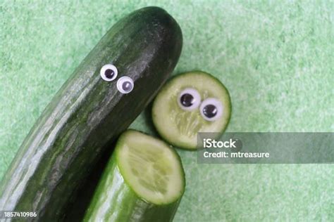 얼룩덜룩 한 녹색 배경에 야채 어린이 건강 식생활 유머러스 한 개념 복사 공간을 가진 전체 오이와 오이 조각으로 만든 재미 있고 만화 캐릭터의 클로즈업 이미지 오이에 대한