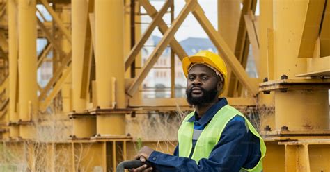 작업복을 입은 아프리카 건설 노동자의 초상화가 작업 도구를 들고 야외에 앉아 카메라를 보고 있다 사진 Unsplash의 산업 이미지