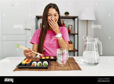 Young Brunette Woman Eating Sushi Using Chopsticks Laughing And Embarrassed Giggle Covering