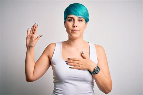 가슴과 열린 손바닥에 손으로 맹세 흰색 배경 위에 캐주얼 티셔츠를 입고 파란색 패션 머리를 가진 젊은 아름다운 여자 충성 약속 선서를 만들기 선서에 대한 스톡 사진 및 기타