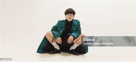 코트를 입은 세련된 청년의 초상화 쪼그리고 앉은 자세 회색 스튜디오 배경 위에 고립 된 포즈 안경에 대한 스톡 사진 및 기타 이미지 Istock
