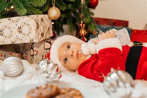 아름다운 어린 소년이 크리스마스를 축하한다 연말 연시 크리스마스 의상을 입은 아기 산타의 옷과 새해 나무 가까이 모피에 선물을 얹은 아기 12월에 대한 스톡 사진 및 기타