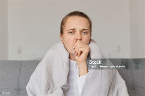 담요 아래에 두통이 있는 아픈 여성의 초상화 기침 입 가까이에 손을 잡고 슬픈 표정을 지으며 인플루엔자 증상을 보입니다 감기와