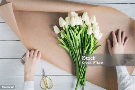 나무 테이블에 팩 공예 종이에 흰색 튤립의 아름다운 꽃다발을 포장 하는 여자 꽃집 플랫 레이 공예에 대한 스톡 사진 및 기타