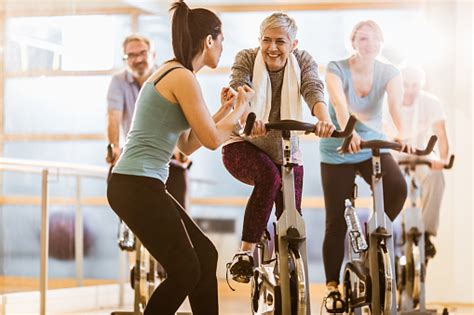 성숙한 운동 여자는 코치가 그녀를 응원 하는 동안 고정 자전거에 회전 자전거 타기에 대한 스톡 사진 및 기타 이미지 자전거 타기 코치 자전거 운동 Istock