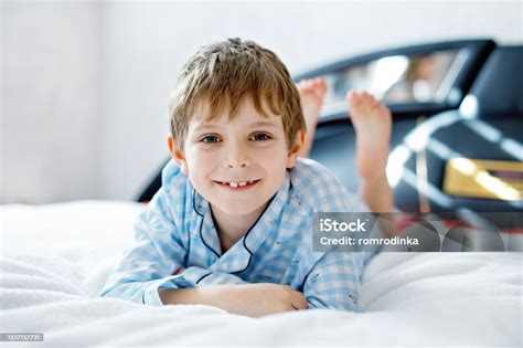 화려한 잠옷을 입고 흰색 침대에서 자고 나서 사랑스러운 행복한 어린 아이 소년 잠옷 파티를 축하하고 카메라를보고 학교 아이 재미 행복 한 아이 재생 및 미소 가정 생활에