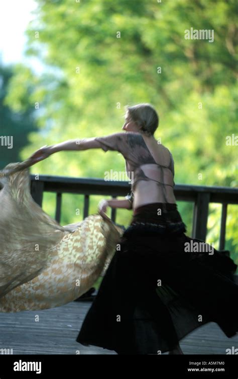 A Woman Is Belly Dancing Against A Background Of Green Trees In This