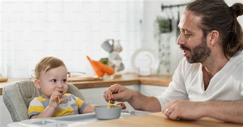 백인 매력적인 아버지는 부엌에서 아기 소년 유아를 돌 봅니다 행복한 가족 사랑하는 남자 아빠가 요리하고 집에서 점심을 먹기 위해 의자에 앉아 있는 동안 어린 아들
