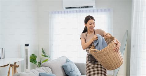 집에서 거실에서 청소하는 아시아 청소 서비스 여성 노동자 아름다운 소녀 가정부 청소부는 행복하다고 느끼고 집안일이나 집안일을 위해 지저분한 더러운 옷을 바구니에 담습니다