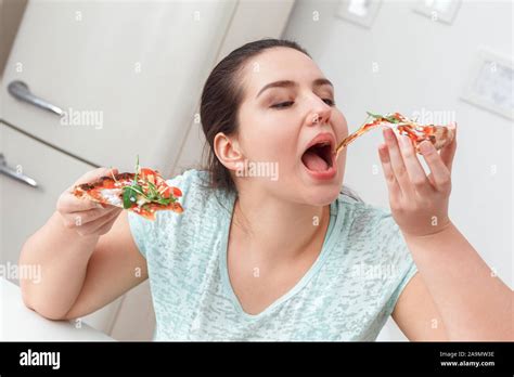 Binge Eating Chubby Girl Sitting At Kitchen Table Eating Pizza Excited Close Up Stock Photo Alamy