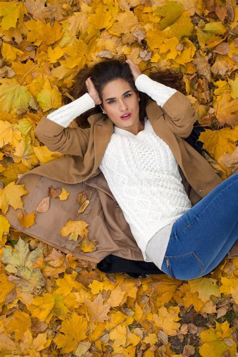 Молодая красивая девушка в голубых джинсах лежа на желтых листьях Стоковое Изображение