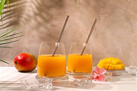 여름 파티 컨셉입니다 햇볕이 잘 드는 주방 테이블에 망고 조각과 얼음을 곁들인 수제 칵테일 주스 또는 레모네이드 상쾌한 여름 다이어트 음료 레시피 디톡스 다이어트와 건강한