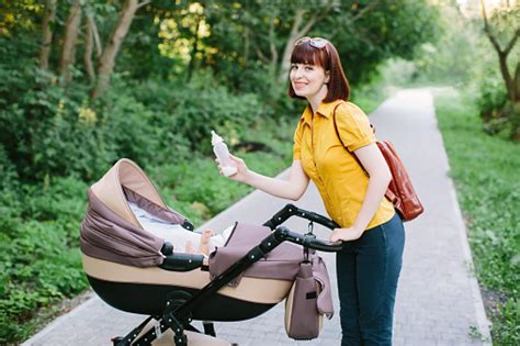공원에서 걷는 유모차에 아기 음식과 아기와 함께 부틀을 들고 아름답고 젊은 여성 어머니 가득 찬에 대한 스톡 사진 및 기타 이미지 가득 찬 걷기 경관 Istock