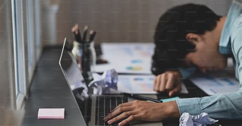 젊은 사업가의 사진은 현대적인 업무용 책상을 배경으로 직장에서 지친 좌절감을 느낀 후 작업 책상에 머리를 숙였습니다 사진 Unsplash의 화난 이미지