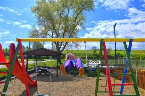 야외 놀이터에서 놀고있는 아이 아이는 학교 나 유치원 마당에서 재생합니다 화려한 스윙에 활동적인 아이 화창한 날씨에 아이들을위한