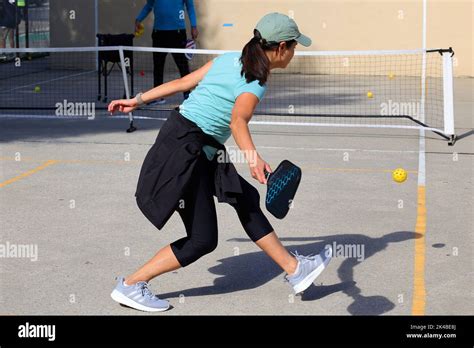 An Asian Woman Playing Pickleball Woman Returns A Pickleball Serve At